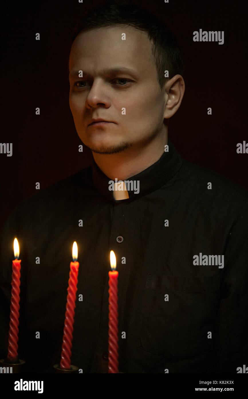 Portrait of handsome catholic priest or pastor with dog collar, dark ...