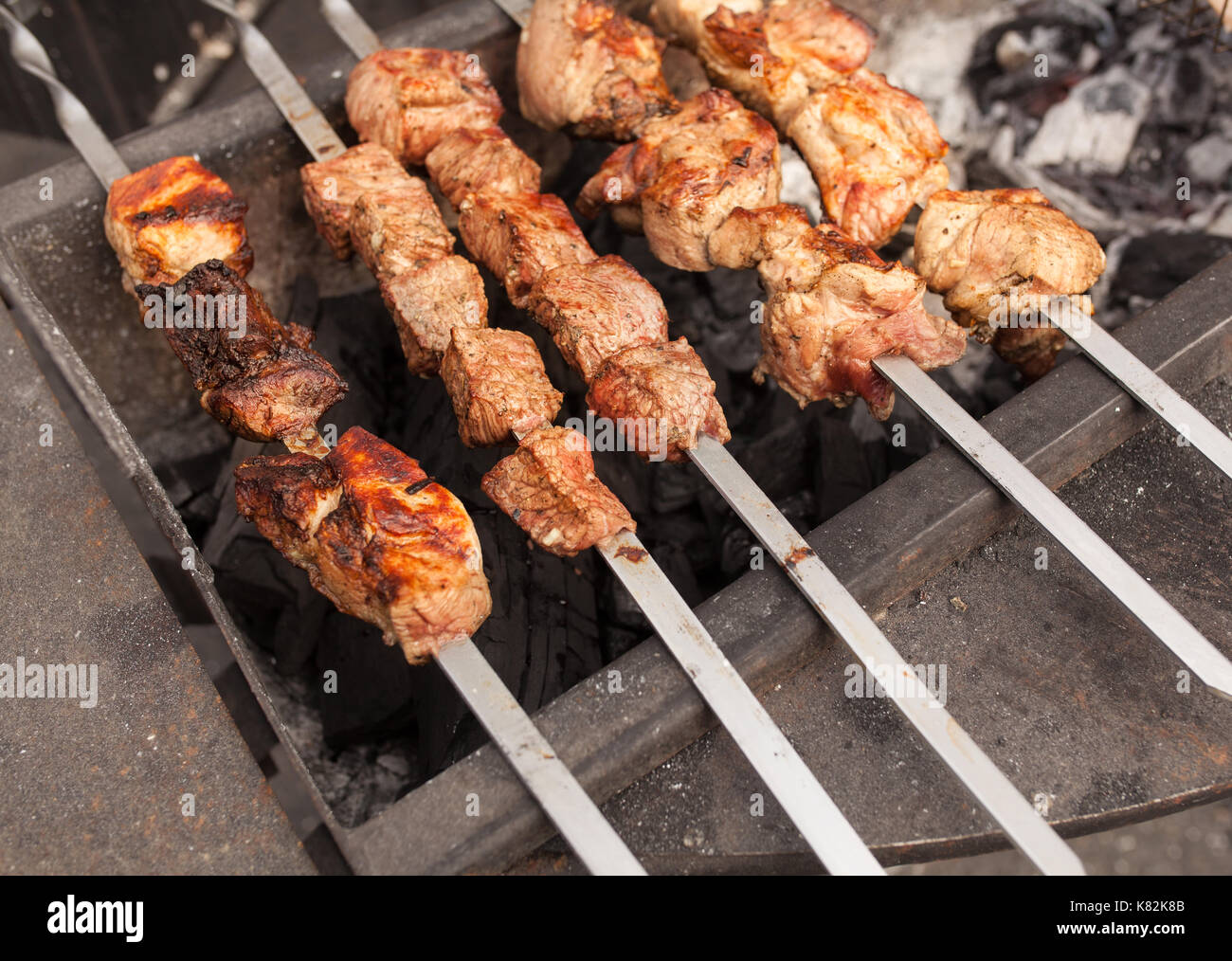 Grilled kebab cooking on metal skewer. Roasted meat cooked at barbecue ...