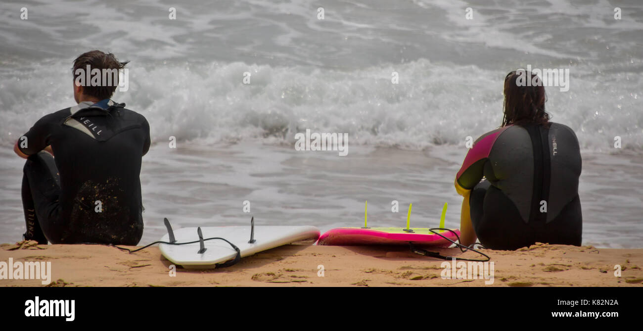 Two surfboard riders sitting on the beach watching the ocean Stock ...