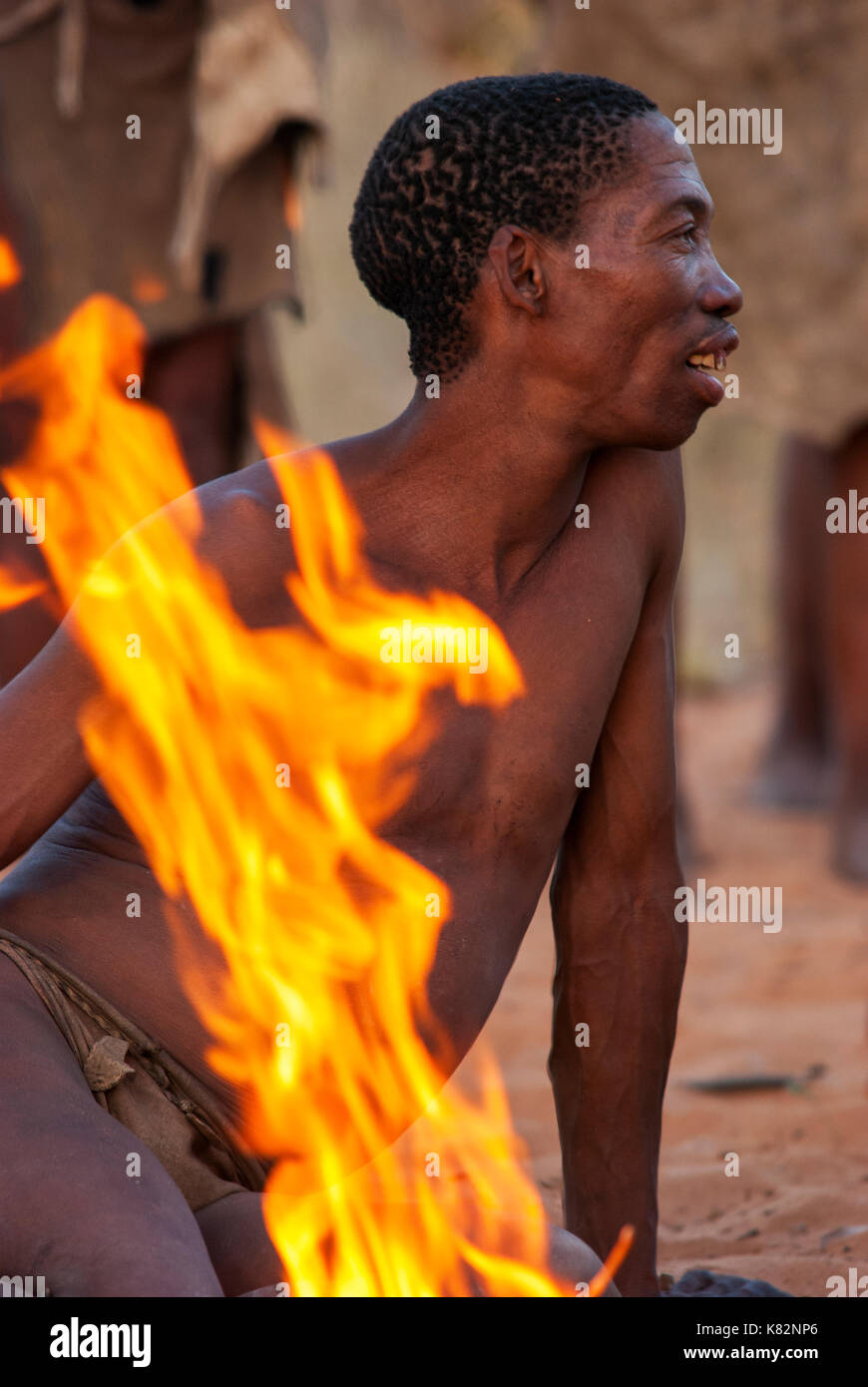 Ju/'Hoansi or San bushmen hunter gathering around camp fire at their ...