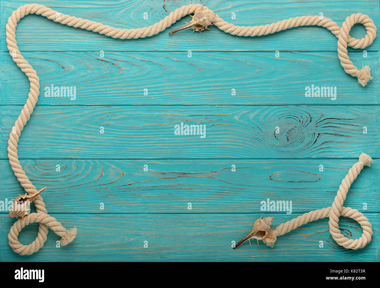 Border with rope and sea shells on a turquoise wooden background. Top ...