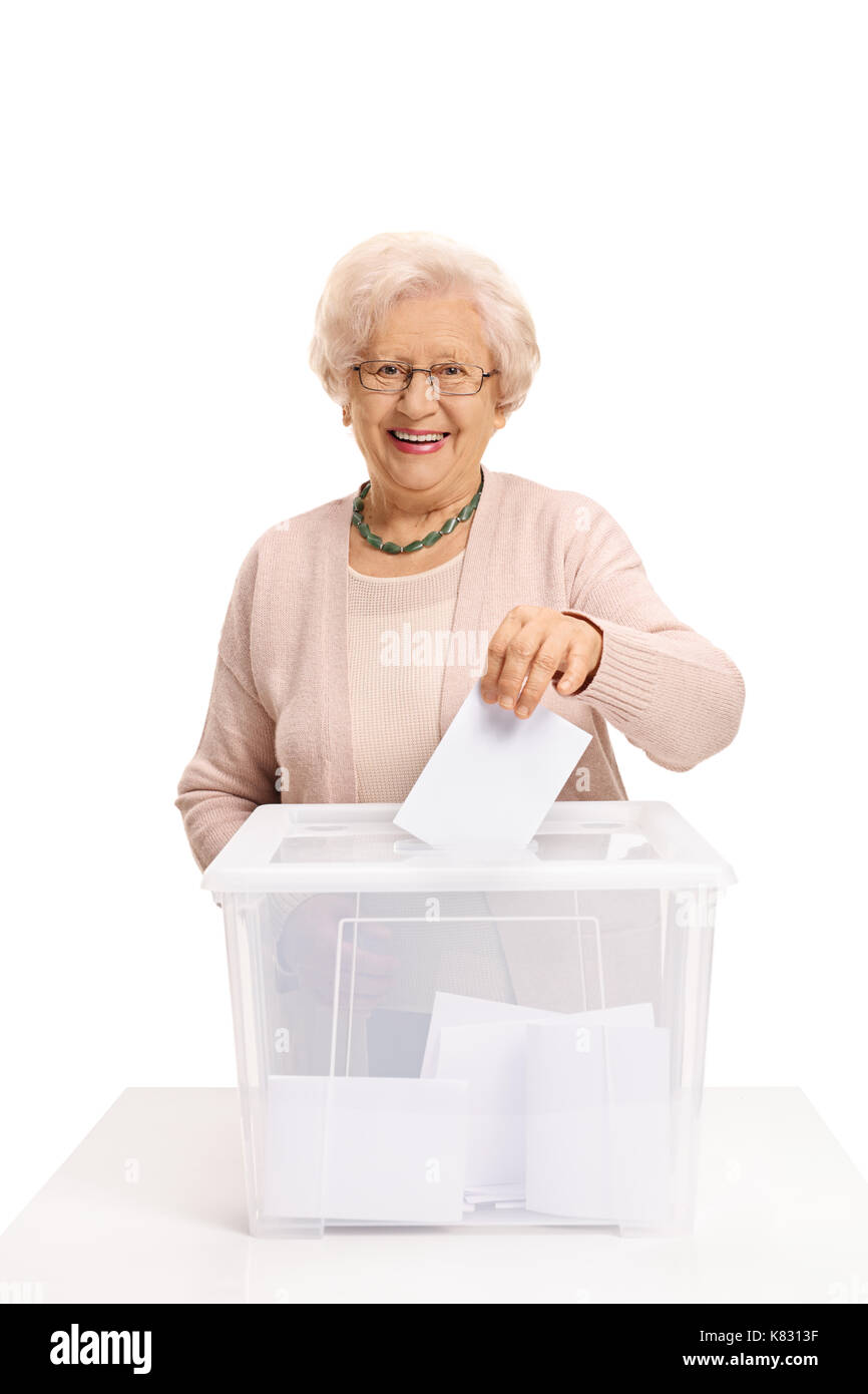 Elderly woman casting a vote into a ballot box and smiling isolated on ...
