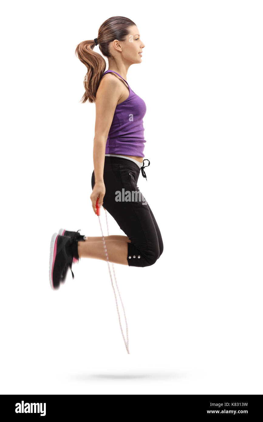 Profile shot of a young woman exercising with a jump rope isolated on ...