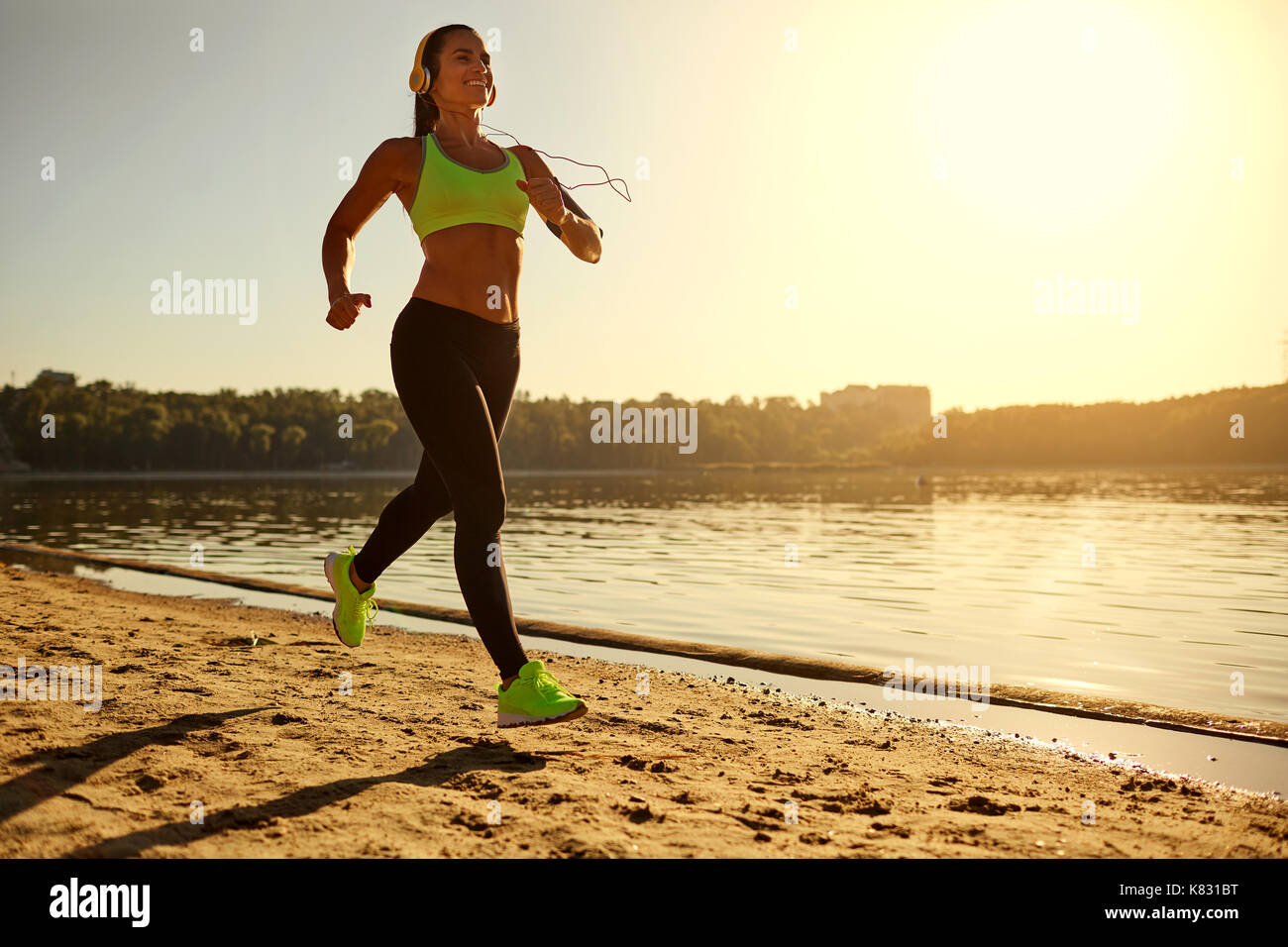 A young woman runner runs at sunset in a park in the lake Stock Photo ...