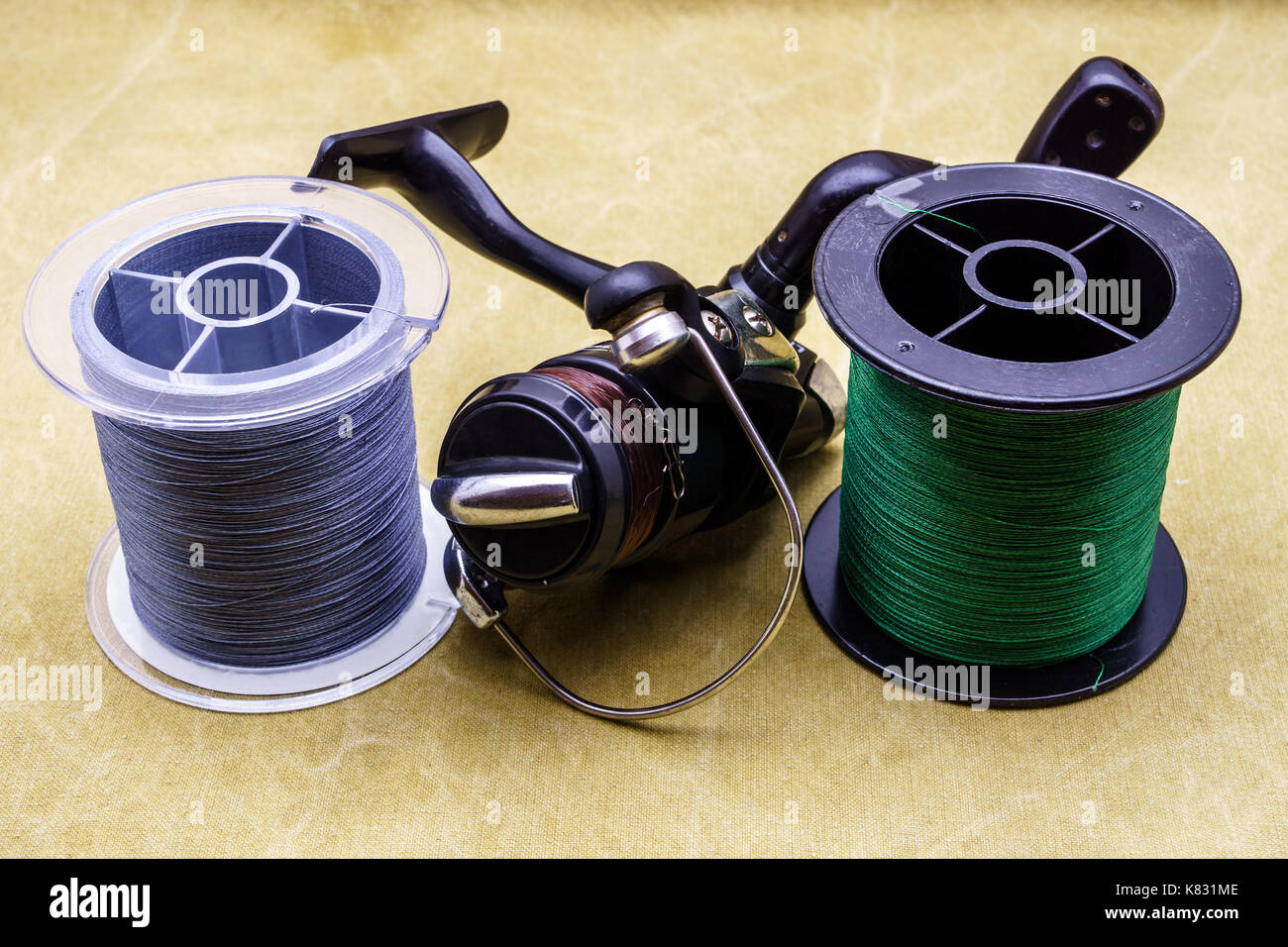 Fishing reel and spools of cords on the background of tarpaulin. Green ...