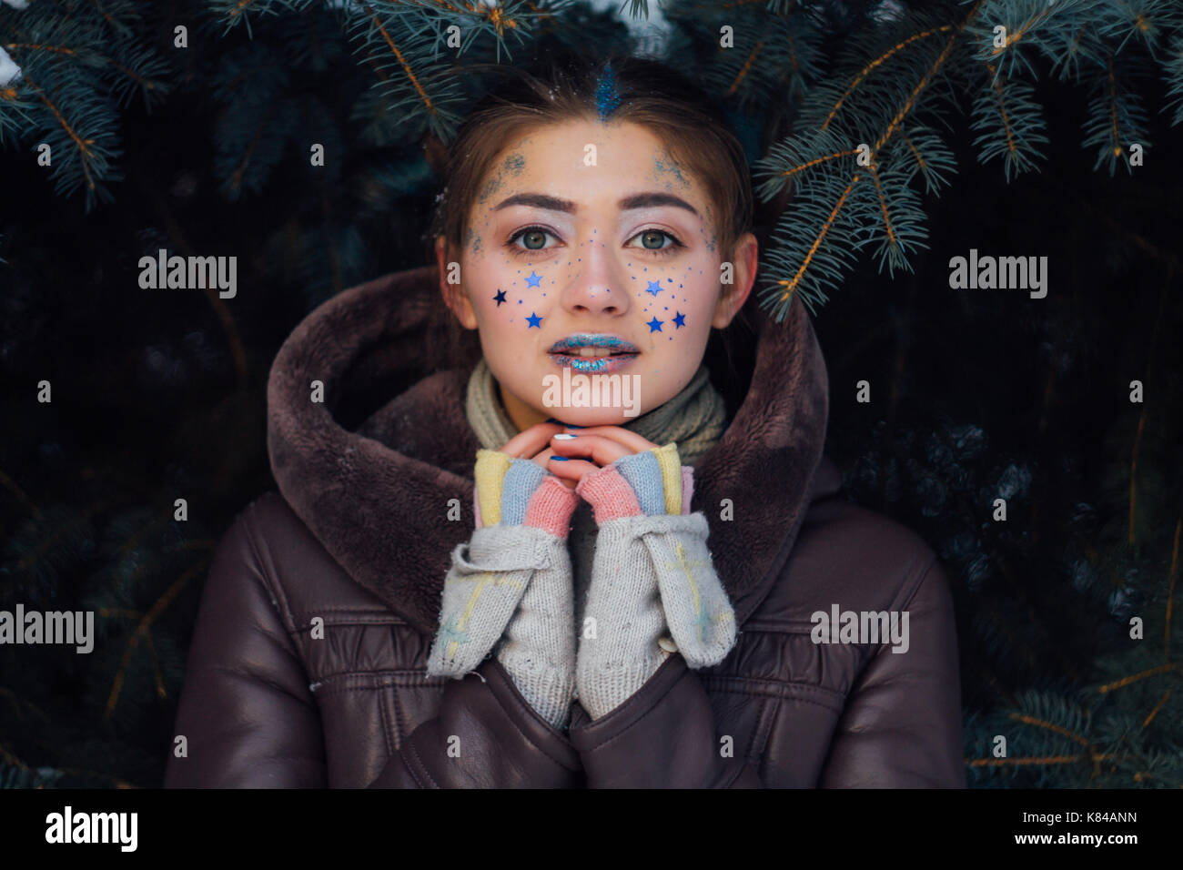Winter portrait of a girl with bright make up and blue stars on face ...