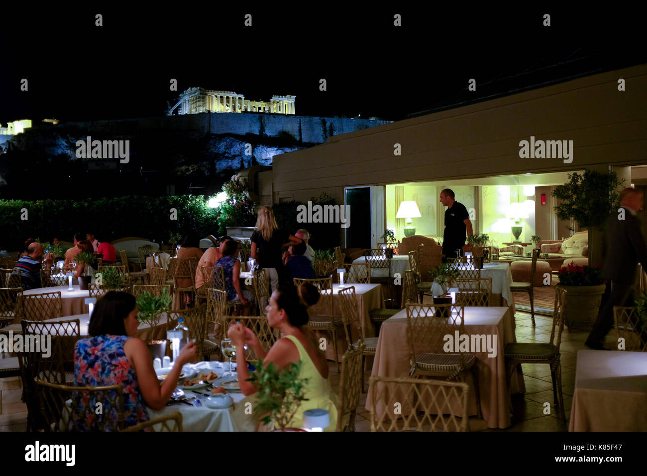 People eat and mingle and look at the Parthenon from the top of a ...