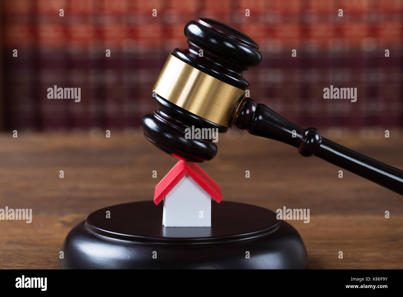 Closeup of wooden mallet being hit on house model at table in courtroom ...