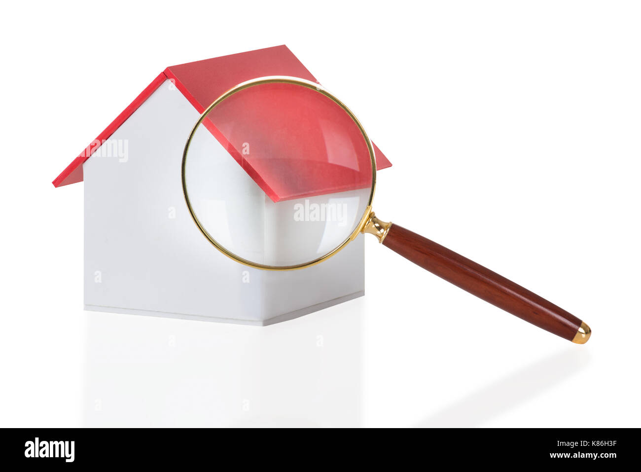 Closeup of magnifying glass and house model isolated over white ...