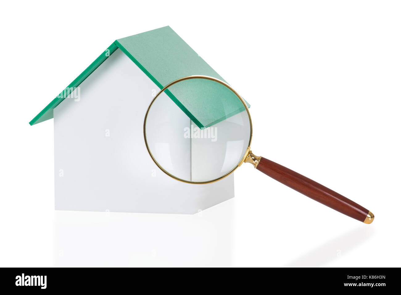 Closeup of magnifying glass and house model isolated over white ...