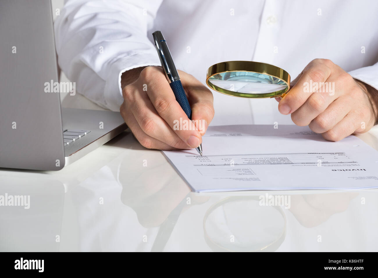Midsection of businessman analyzing invoice with magnifying glass by ...
