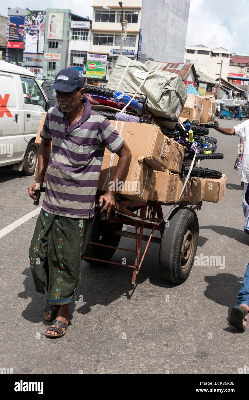 A market trader pulling is barrow loaded with goods in Pettah Market in ...