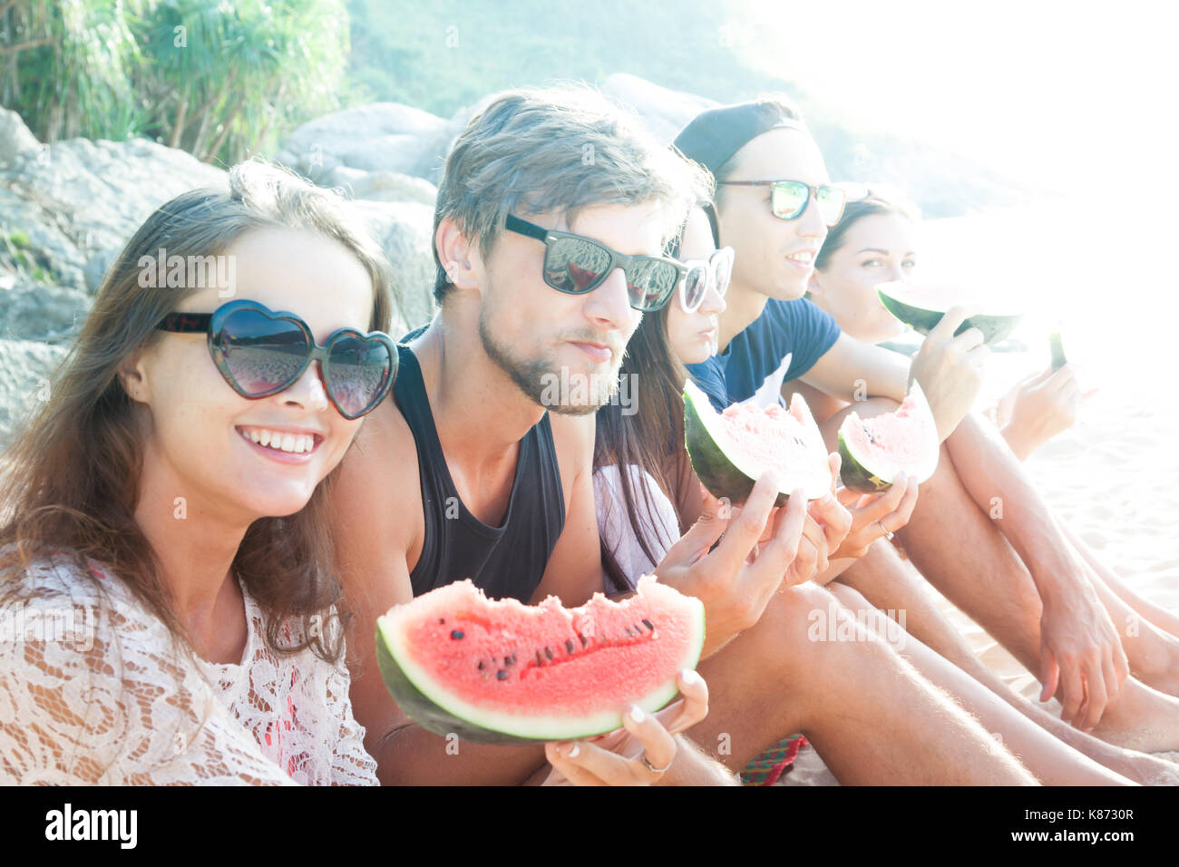 Happy young friends eating watermelon on beach Stock Photo - Alamy
