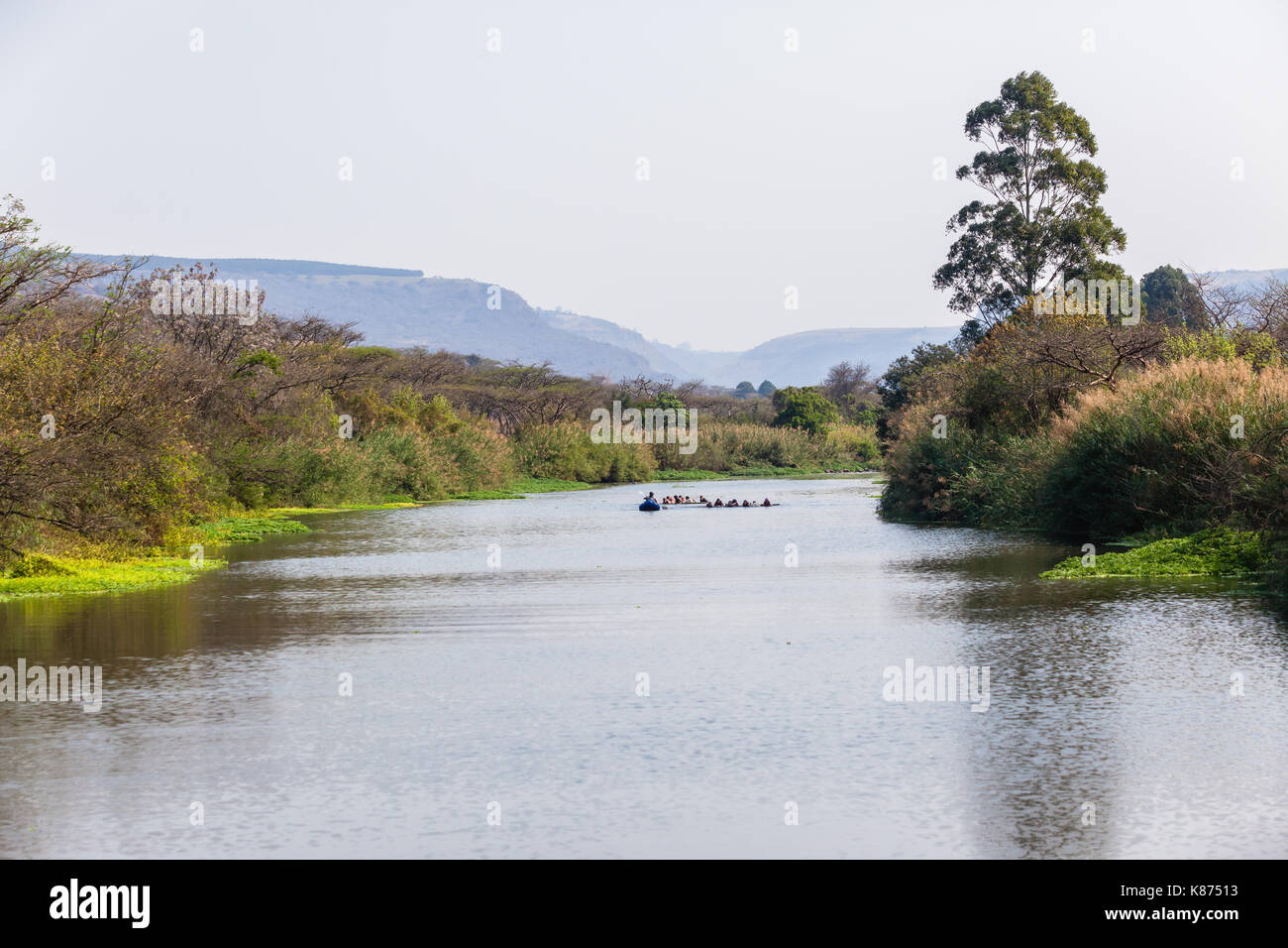 River rafting distant teenagers on glassy smooth waters in scenic rural ...