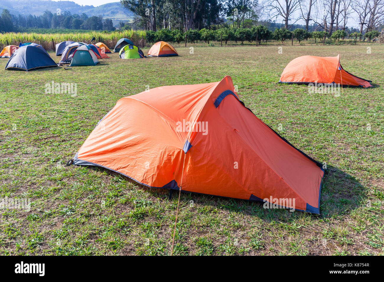 Camping tents a dozen spread over grass field rural mountain ...