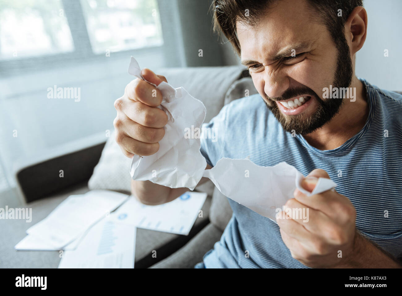 Unhappy furious man tearing apart crumpled paper Stock Photo - Alamy