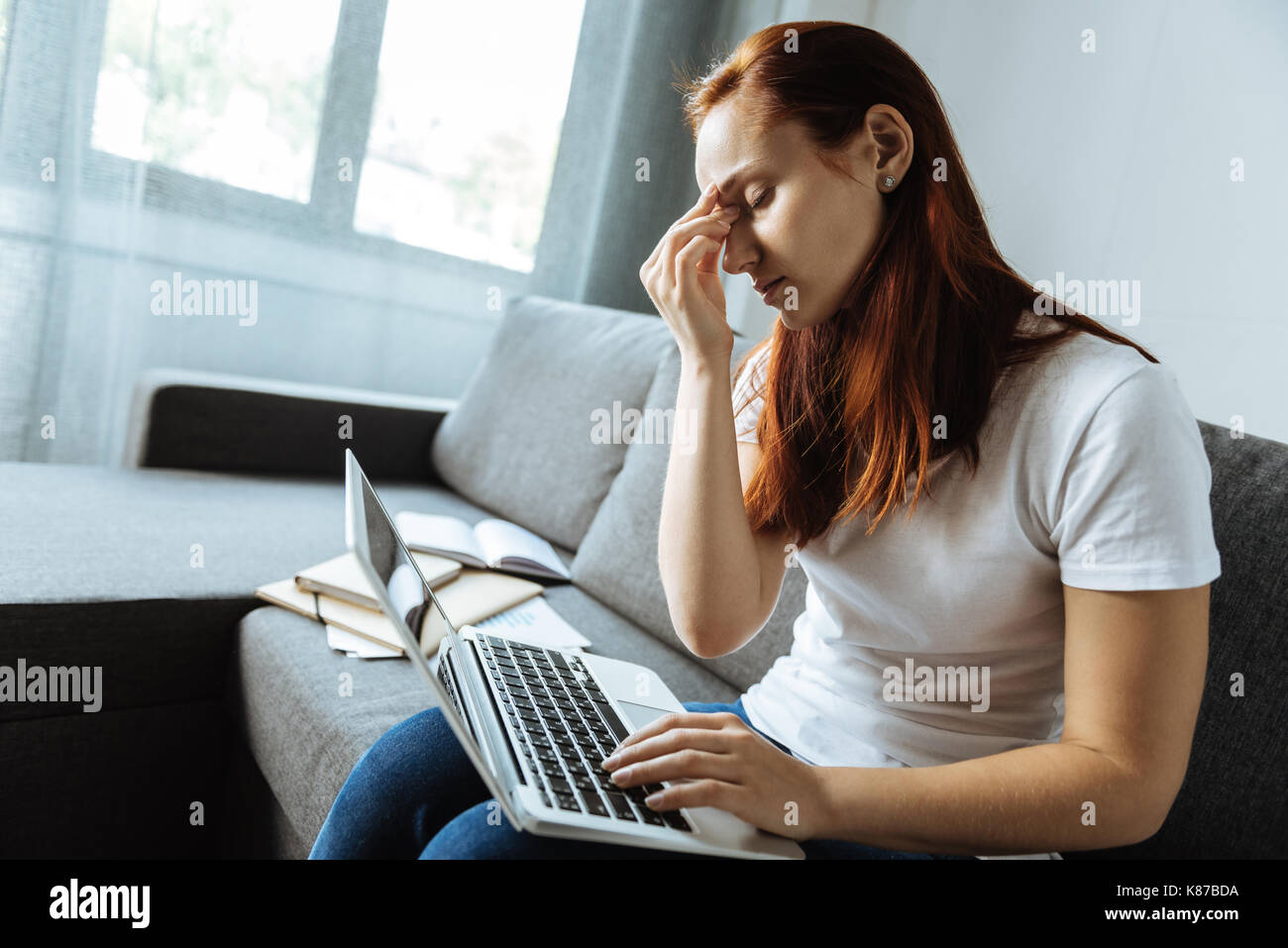 Sad tired woman holding her bridge of nose Stock Photo - Alamy