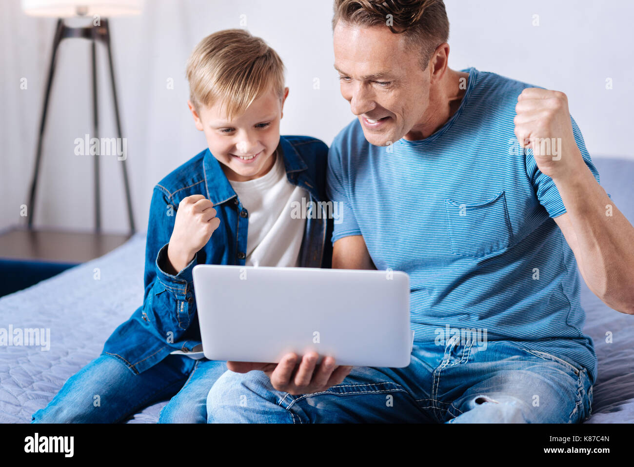 Joyful father and son celebrating goal while watching football online ...