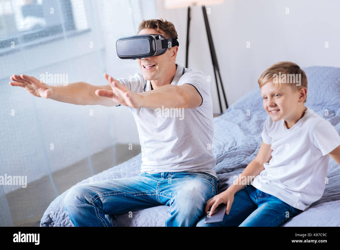 Happy man playing with a VR headset on bed Stock Photo - Alamy