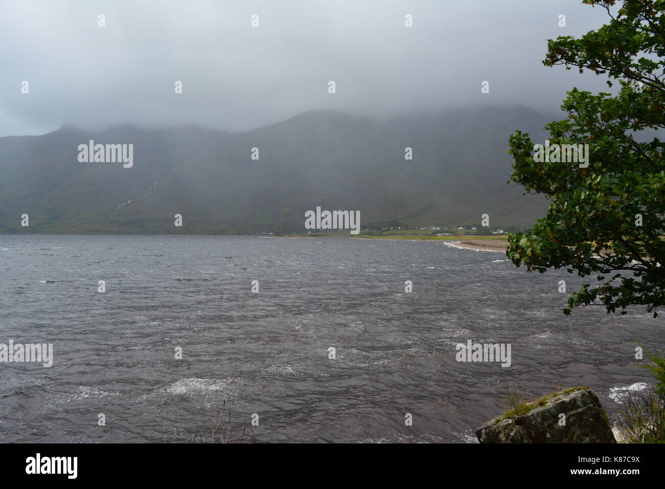 Heavy rainfall and wind on loch lake with mountains in the background ...