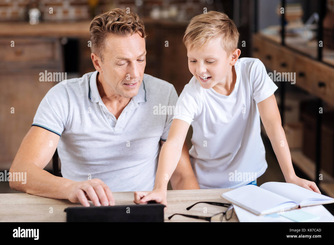 Pre-teen boy explaining father how to use tablet Stock Photo - Alamy