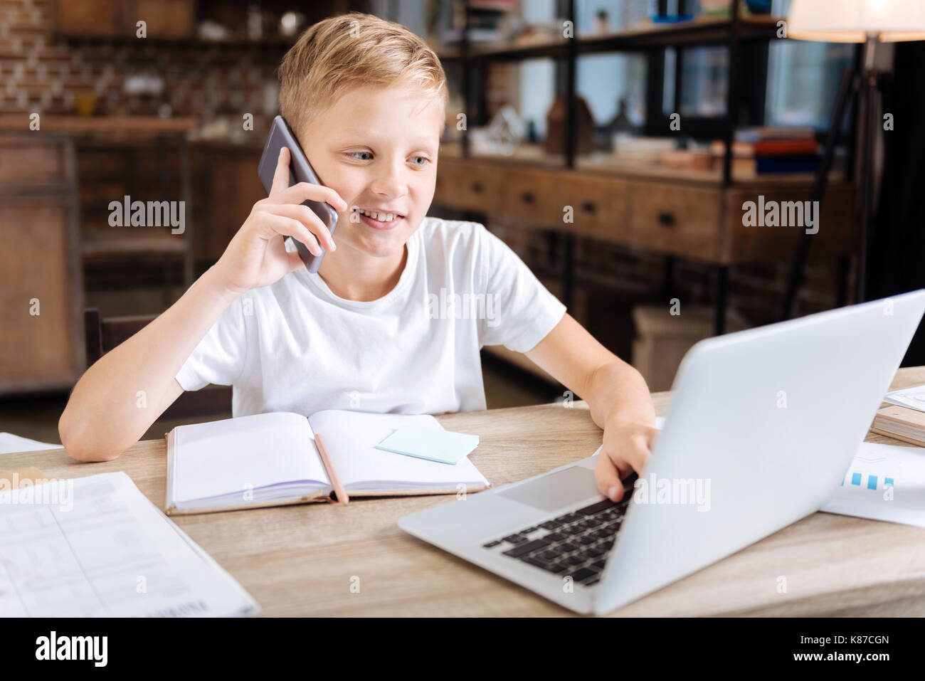 Pre-teen boy making phone call while using laptop Stock Photo - Alamy