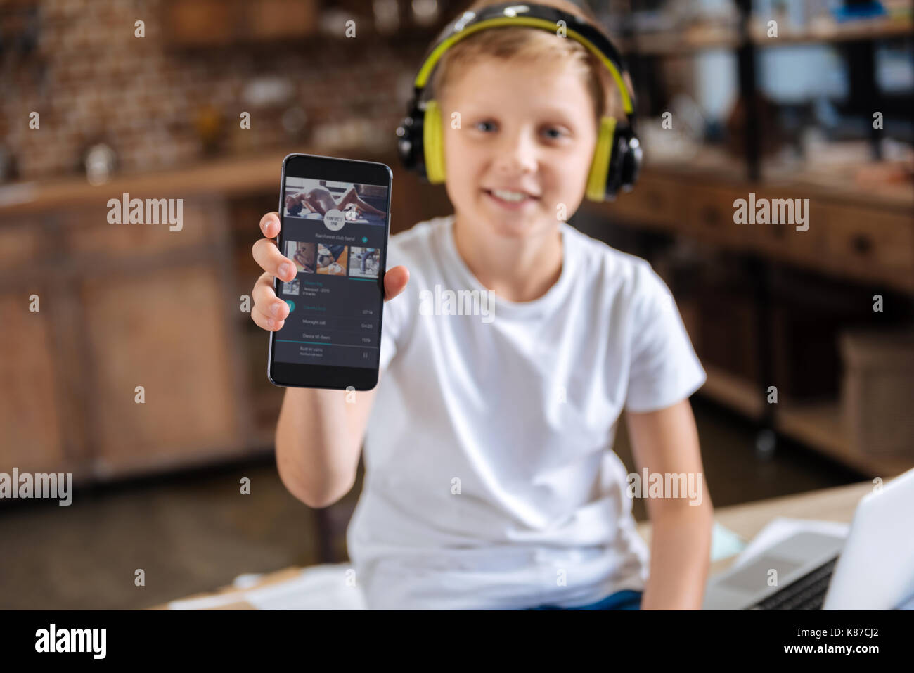 Cheerful boy showing phone with music streaming app Stock Photo - Alamy