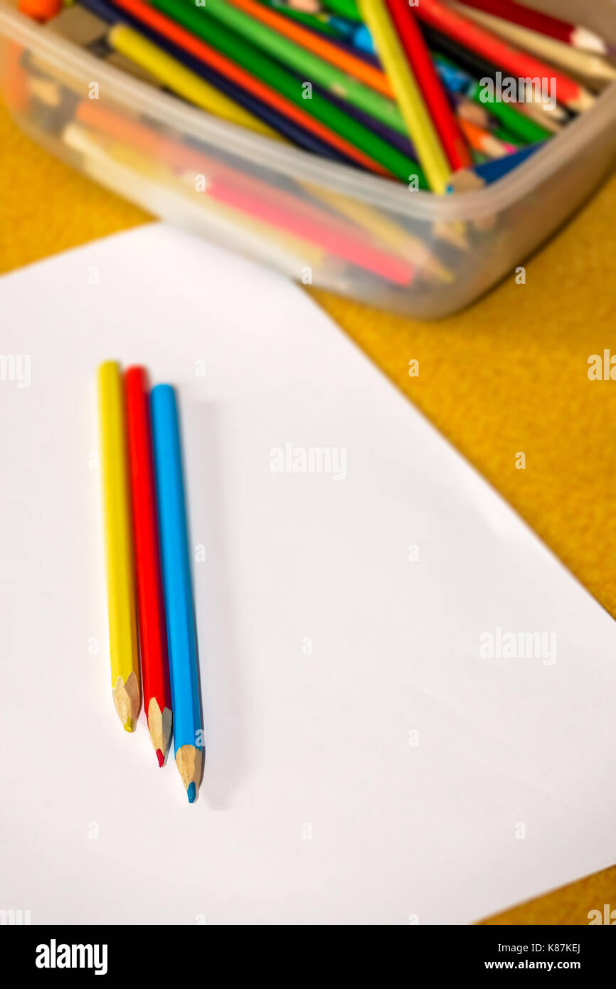 Red, yellow and blue crayons and white paper sheet on the desk Stock ...