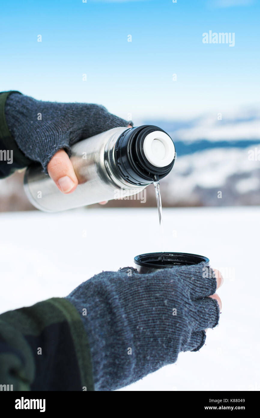 Man using thermos bottle on the snowy mountain Stock Photo - Alamy