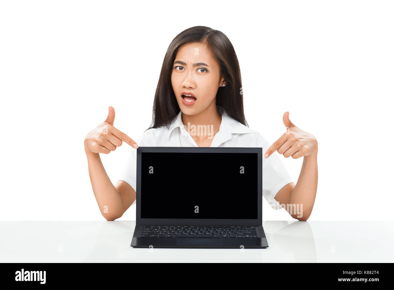 Portrait of frustrated woman pointing fingers at blank laptop screen ...