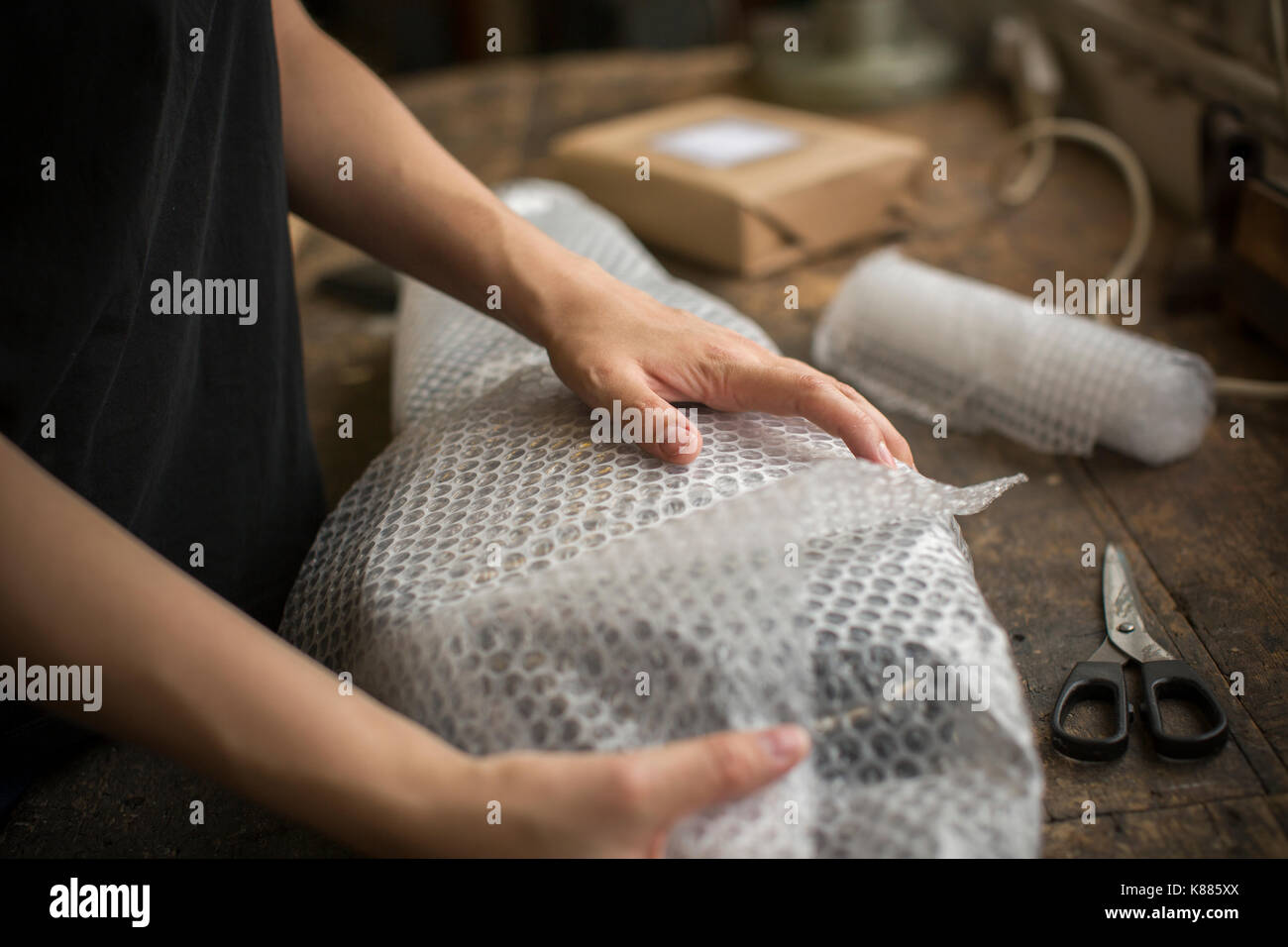 A woman wrapping an item in bubble wrap, a parcel being prepared for ...