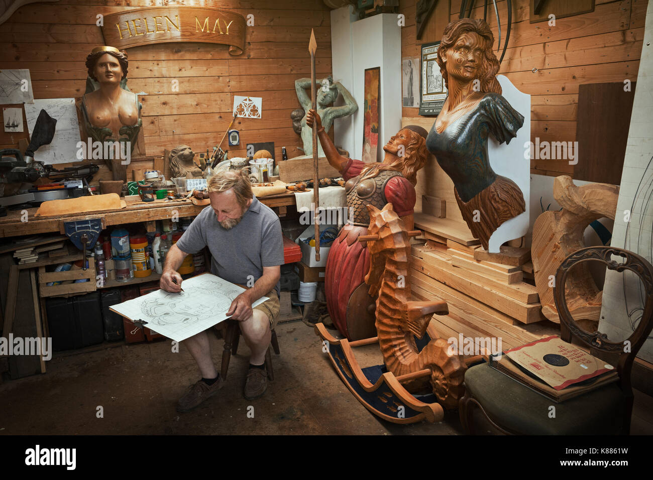 A craftsman, woodworker seated on a stool in a workshop working on a ...