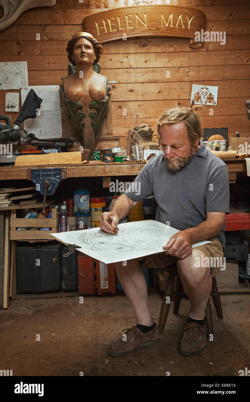 A craftsman, woodworker seated on a stool in a workshop working on a ...