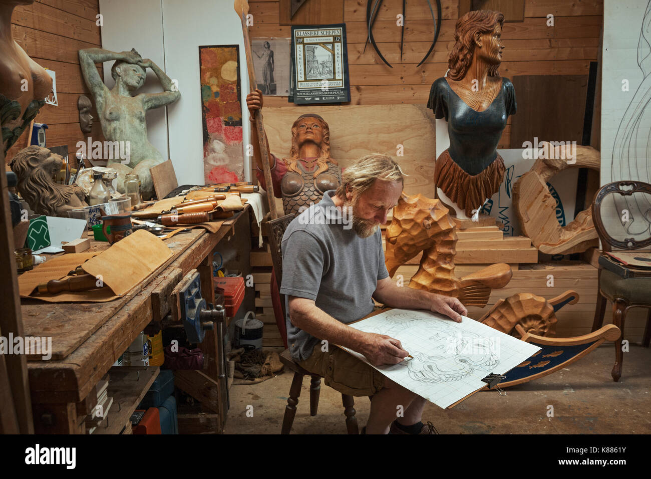 A craftsman, woodworker seated on a stool in a workshop working on a ...