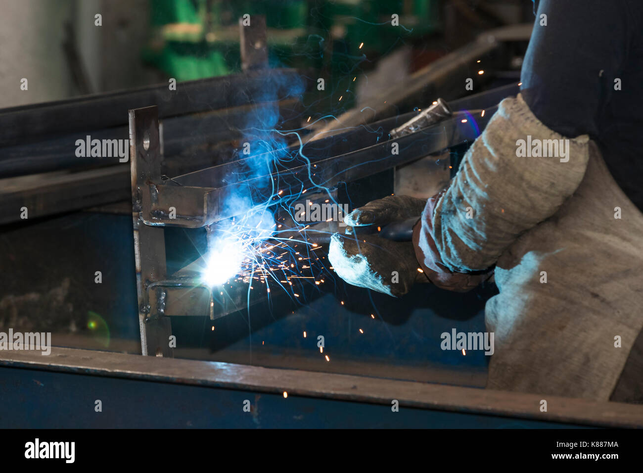 Metalworking shop workers work behind machines and apparatuses to ...