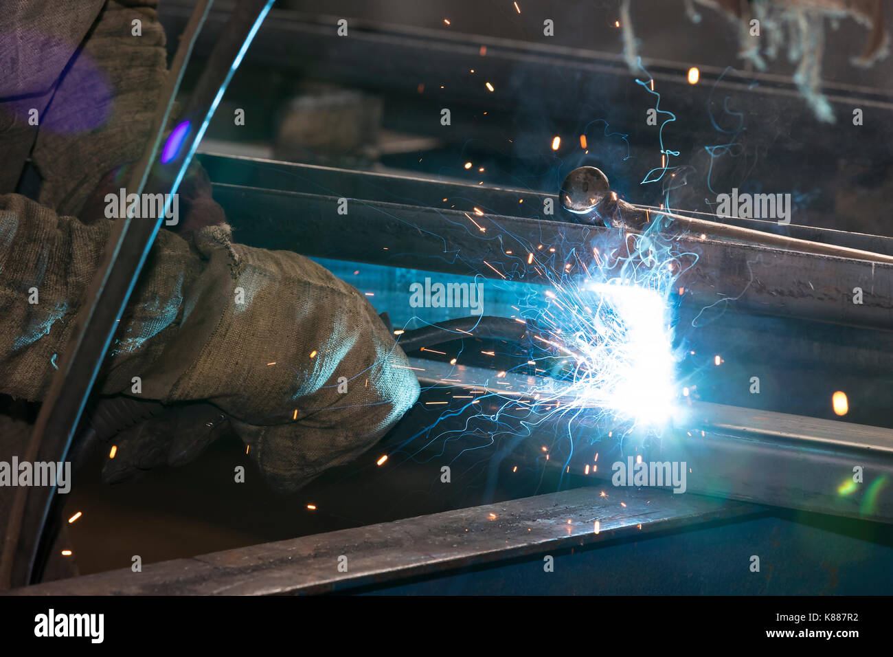 Metalworking shop workers work behind machines and apparatuses to ...