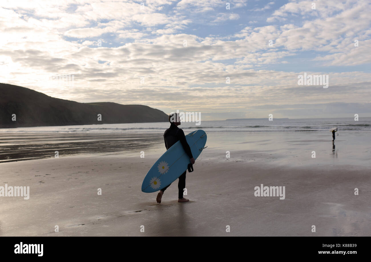 A family getting ready to surf carrying surfboards across the beach ...