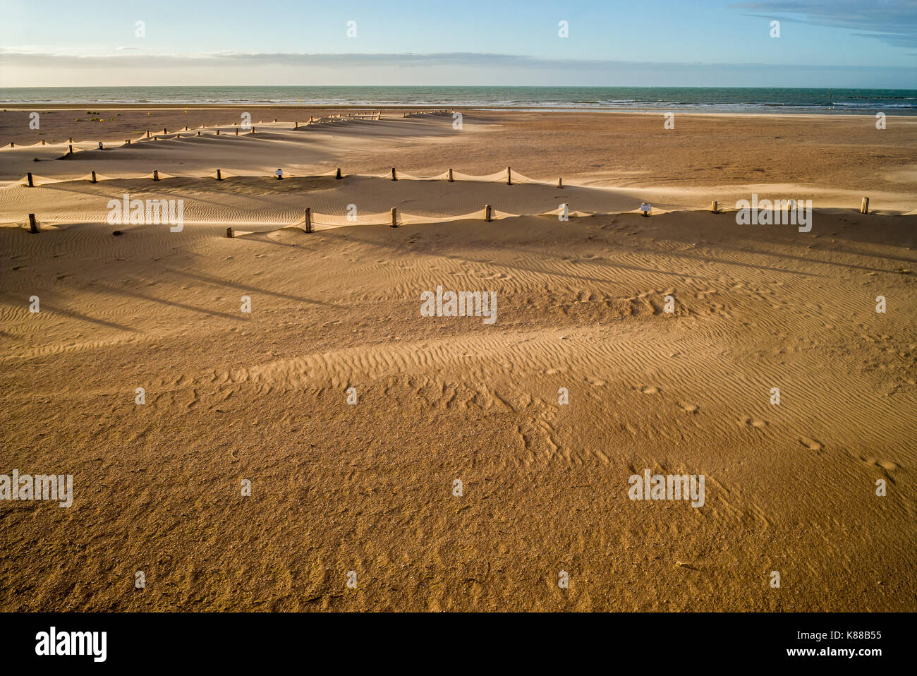 Wooden poles of the sea defences line the beach at Malo Les Bains beach ...