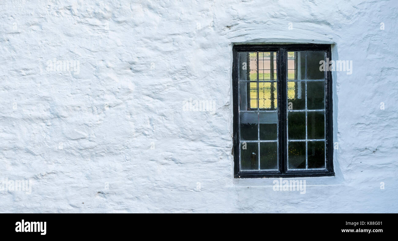 white, stone wall with a black window frame inset into the stone of an ...