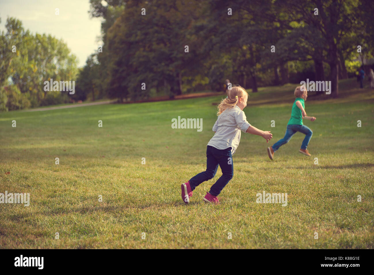 Two happy children running in park in sunset Stock Photo - Alamy