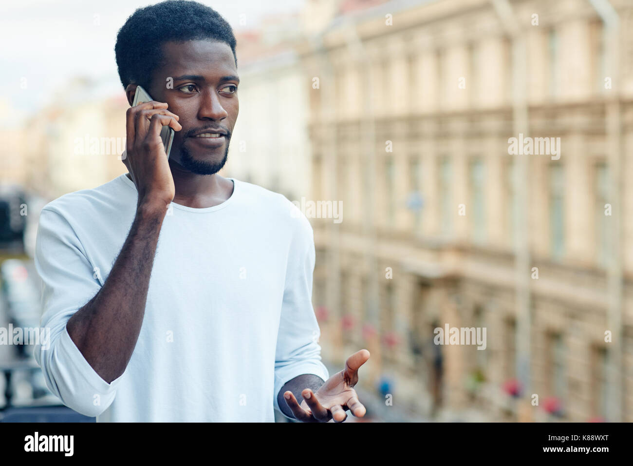 Busy guy in homewear speaking on smartphone on balcony Stock Photo - Alamy