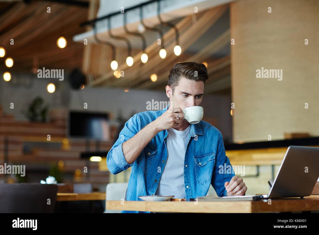 Young manager with stylish haircut enjoying fragrant coffee while ...