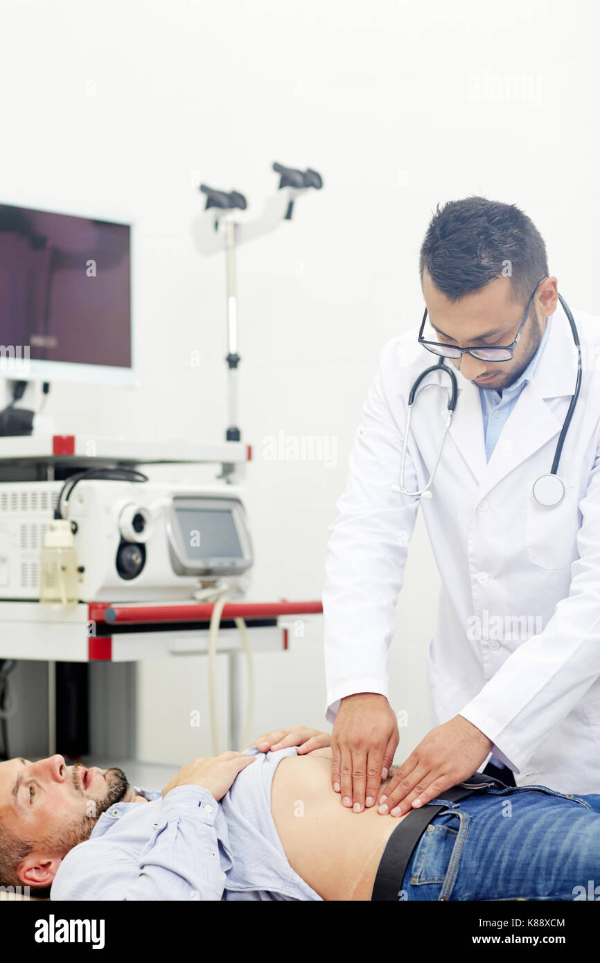 Medical specialist examining stomach of patient with abdominal pain ...