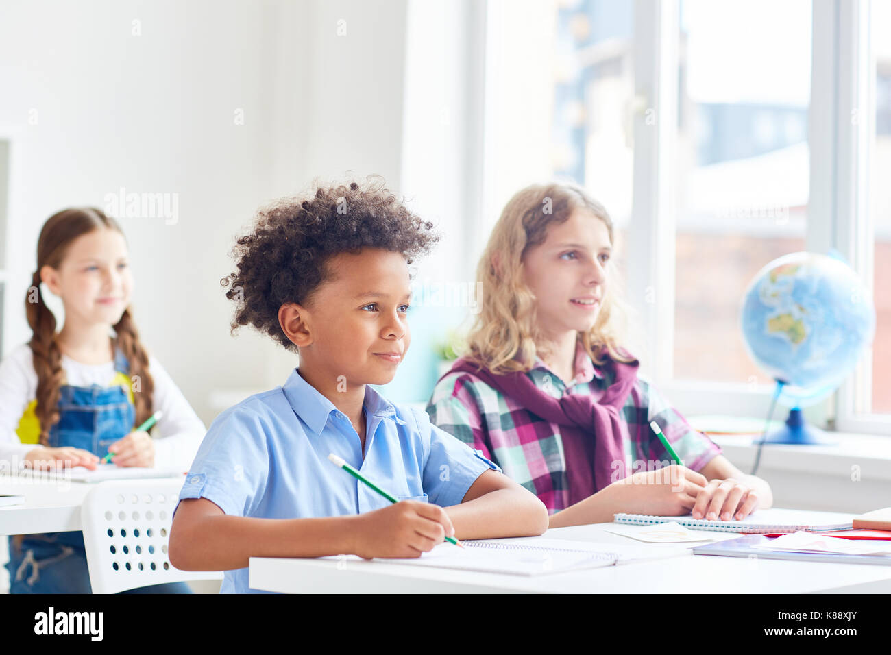 Clever classmates looking attentively at blackboard at lesson Stock ...