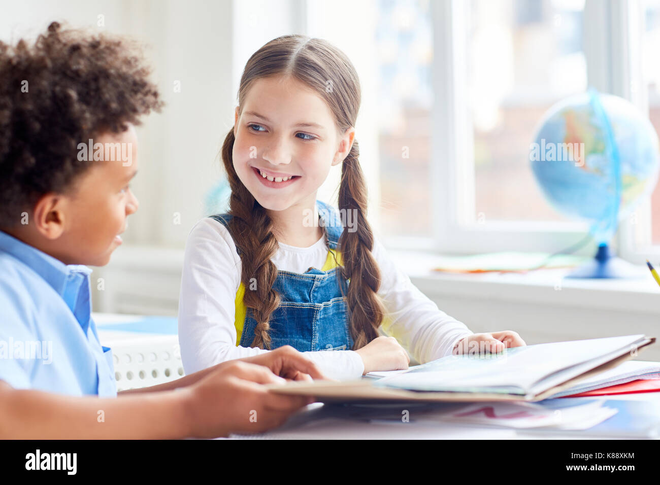 Intercultural classmates discussing story from book at lesson Stock ...