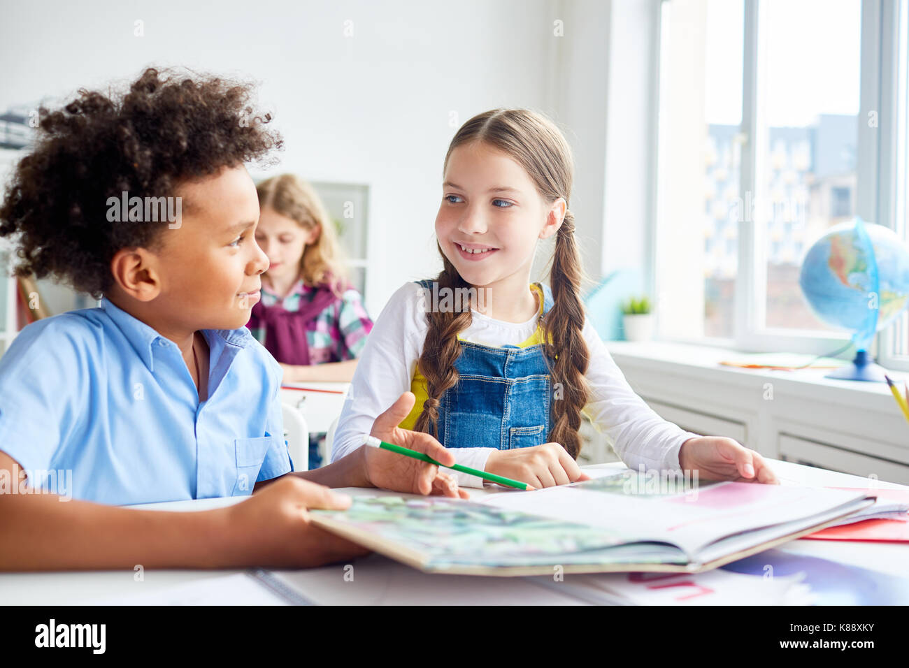 Friendly classmates with open book of tales having discussion on ...