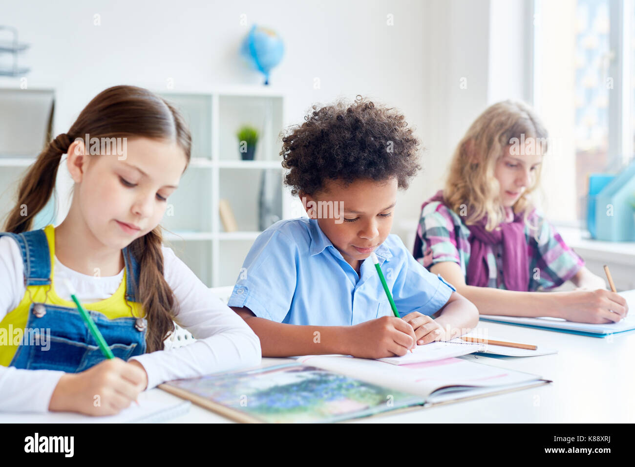 Group of schoolmates with pencils drawing at free topic lesson Stock ...