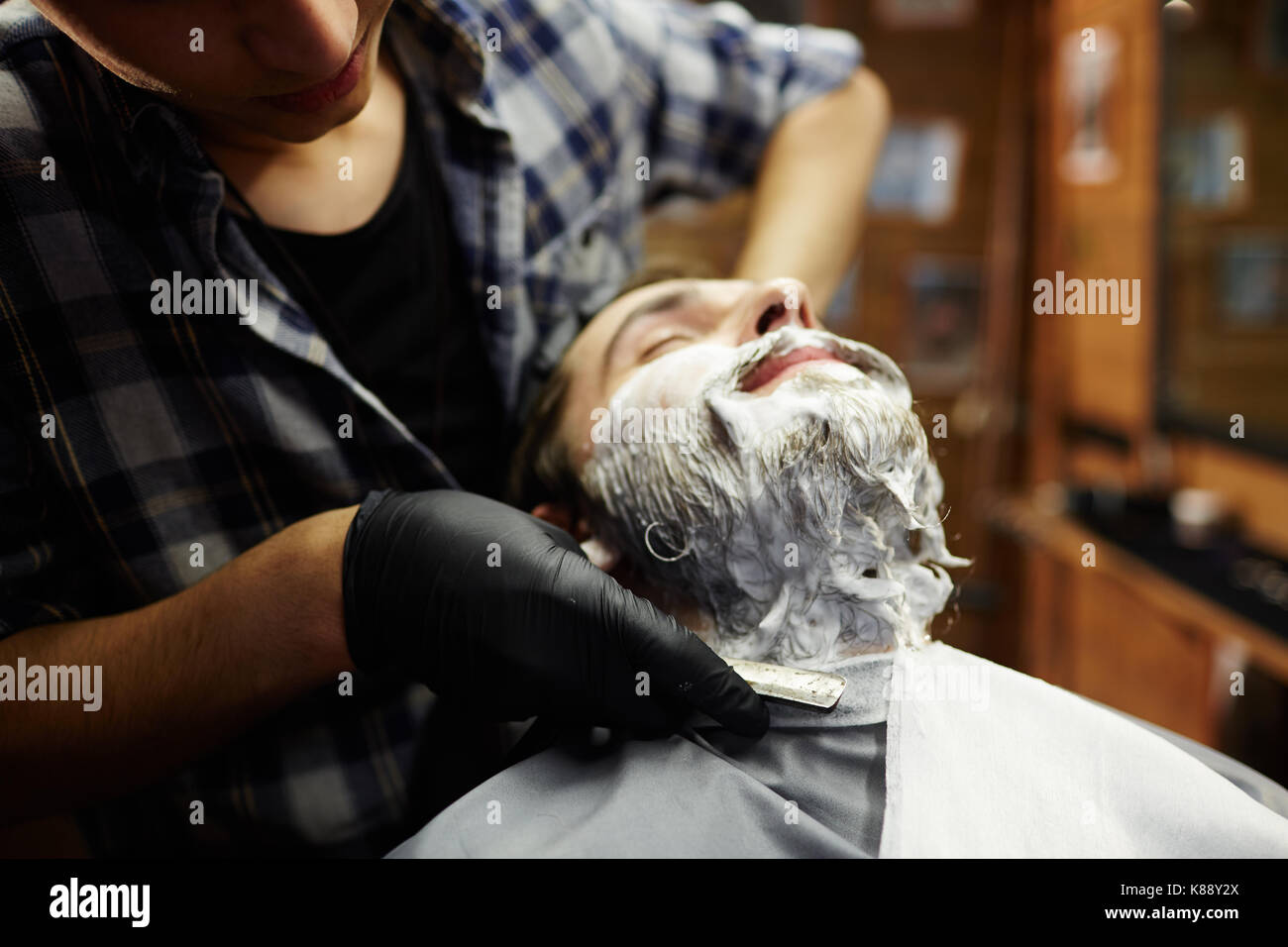 Bearded man being shaven with sharp dangerous razor by professional ...