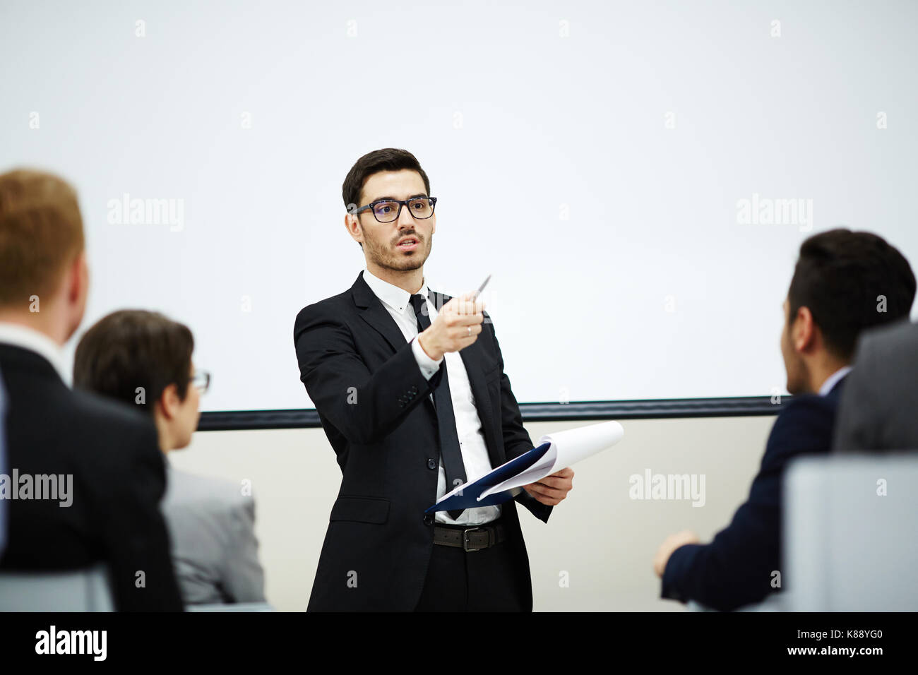 Confident coach pointing at one of listeners while making report at ...