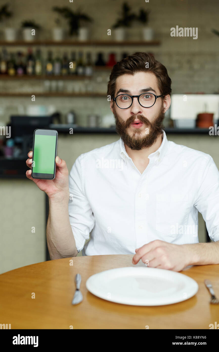 Young man showing menu of restaurant in his smartphoneafter eating ...